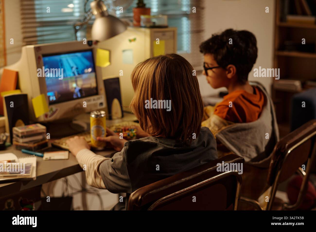 Two children engrossed in playing video games on a computer in a cozy ...
