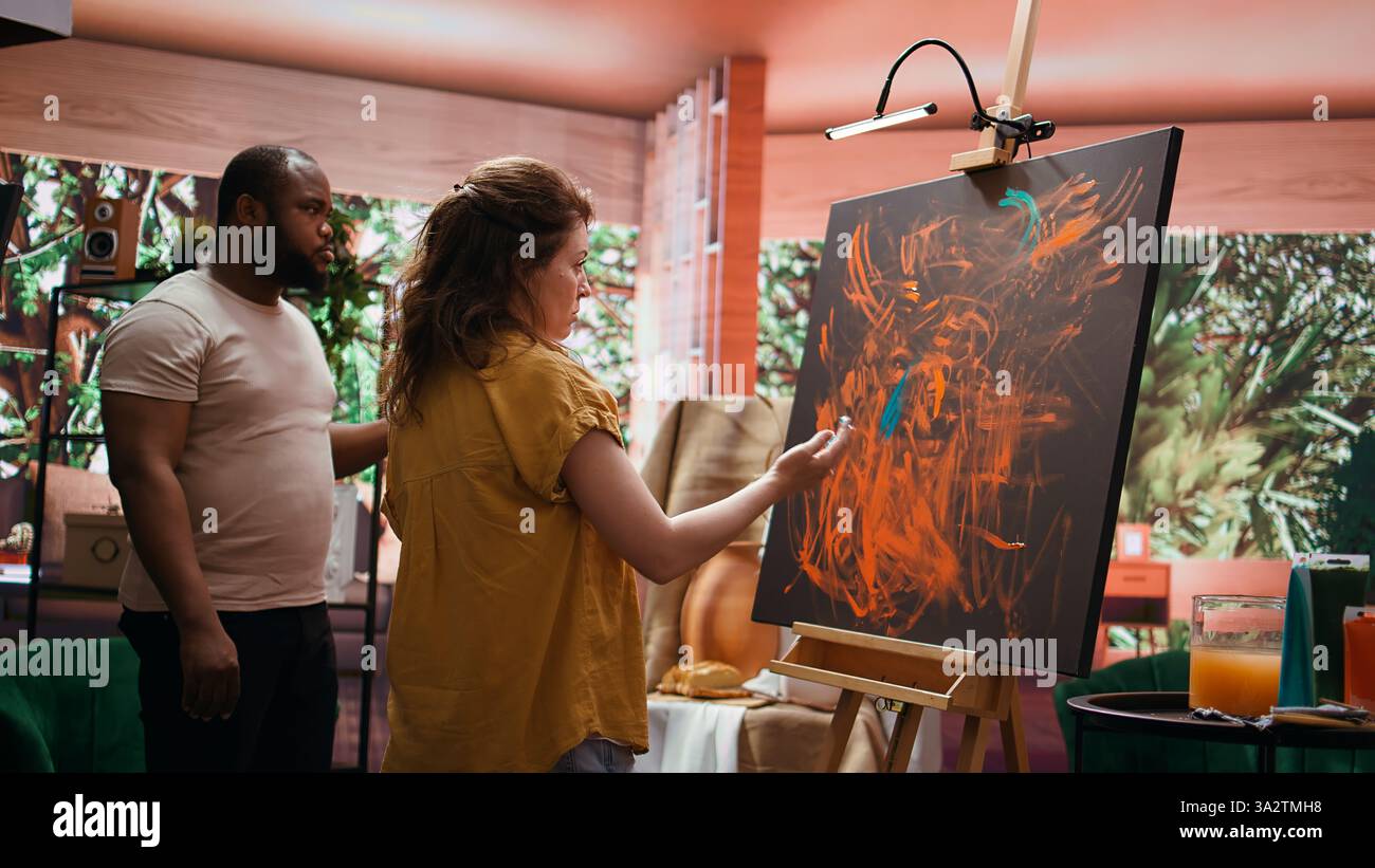 Team of artists in a gallery atelier working on new art piece, using finger painting technique ...