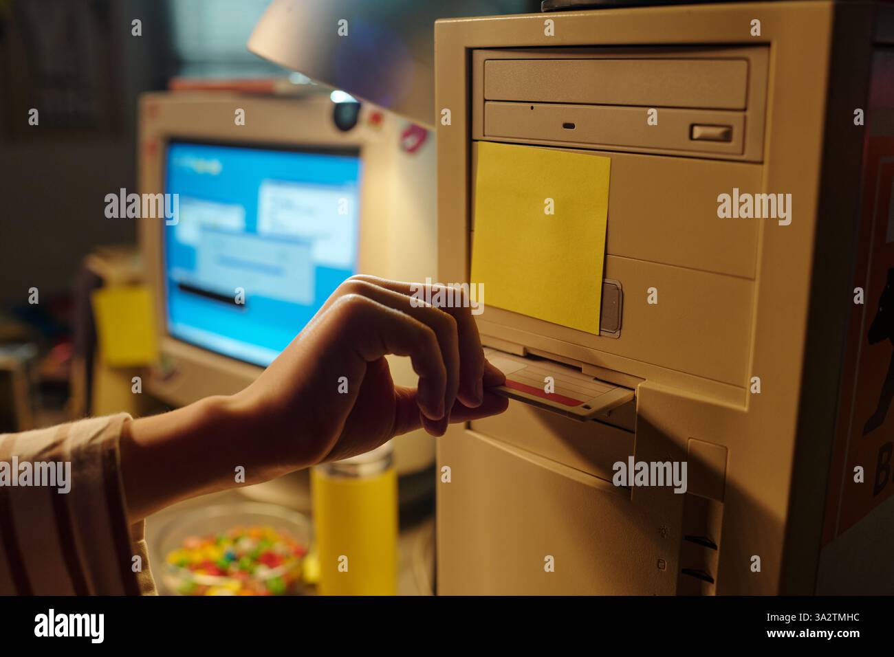 Hand inserting floppy disk into vintage computer with background ...