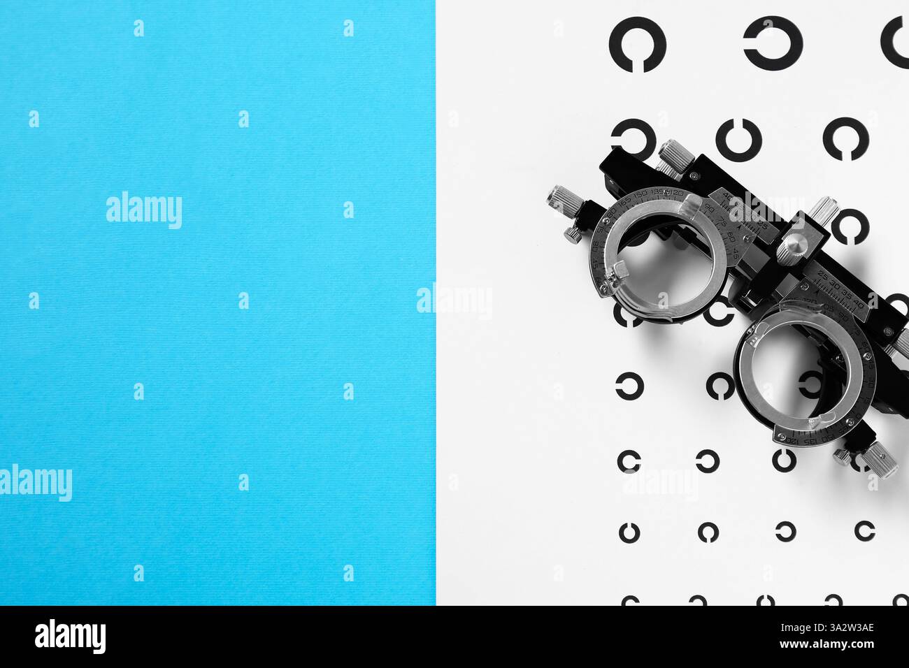Vision test chart and trial frame on light blue background, top view ...
