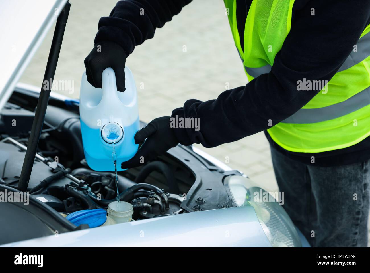 Man pouring windshield washer from plastic canister into car reservoir ...