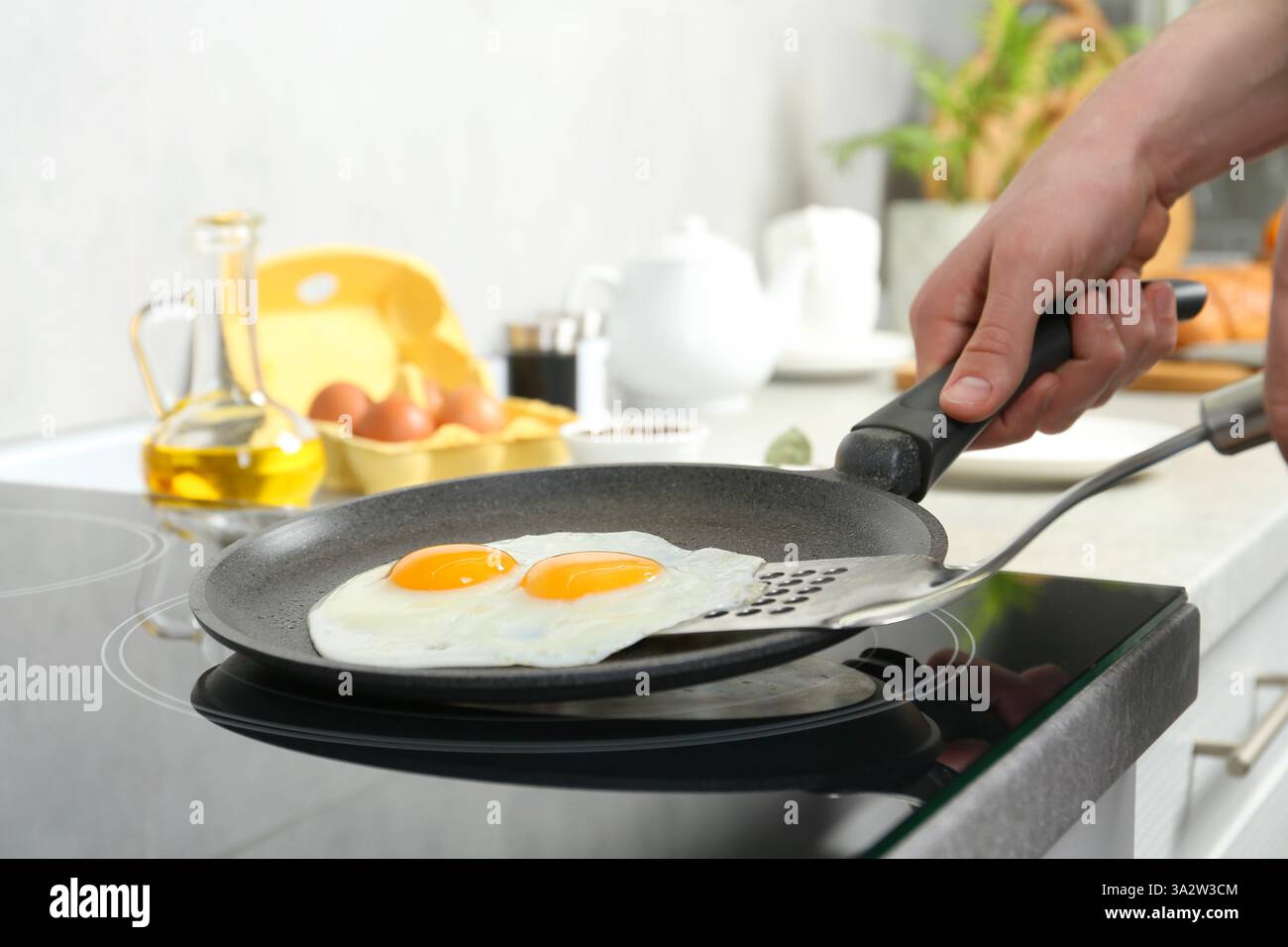 Man taking fried eggs from frying pan in kitchen, closeup Stock Photo ...