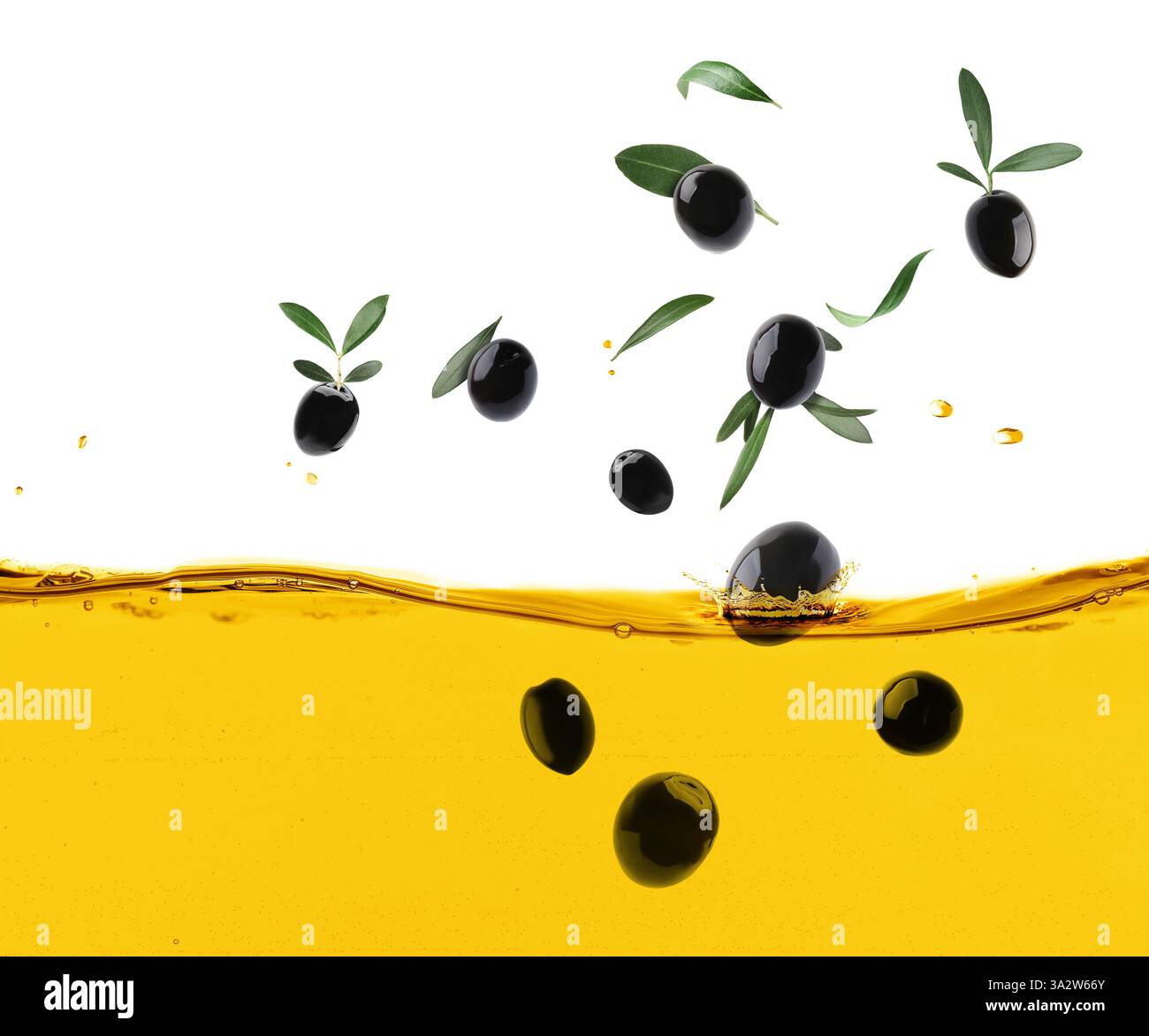 Black olives and green leaves falling into cooking oil on white ...