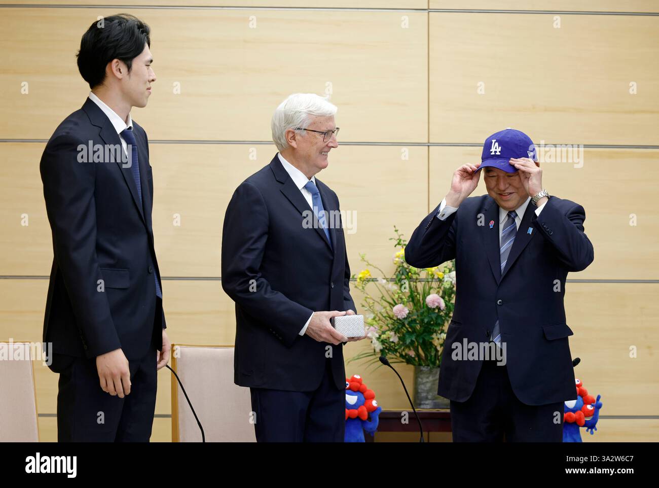 Japan's Prime Minister Shigeru Ishiba, right, puts on a baseball cap ...