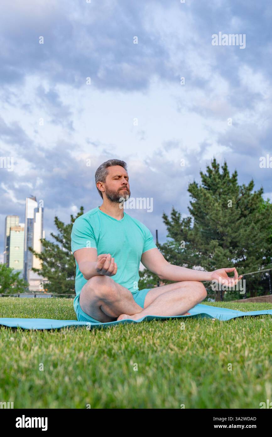 Latin Man meditating in lotus pose in grass outdoors. Sportsman doing ...