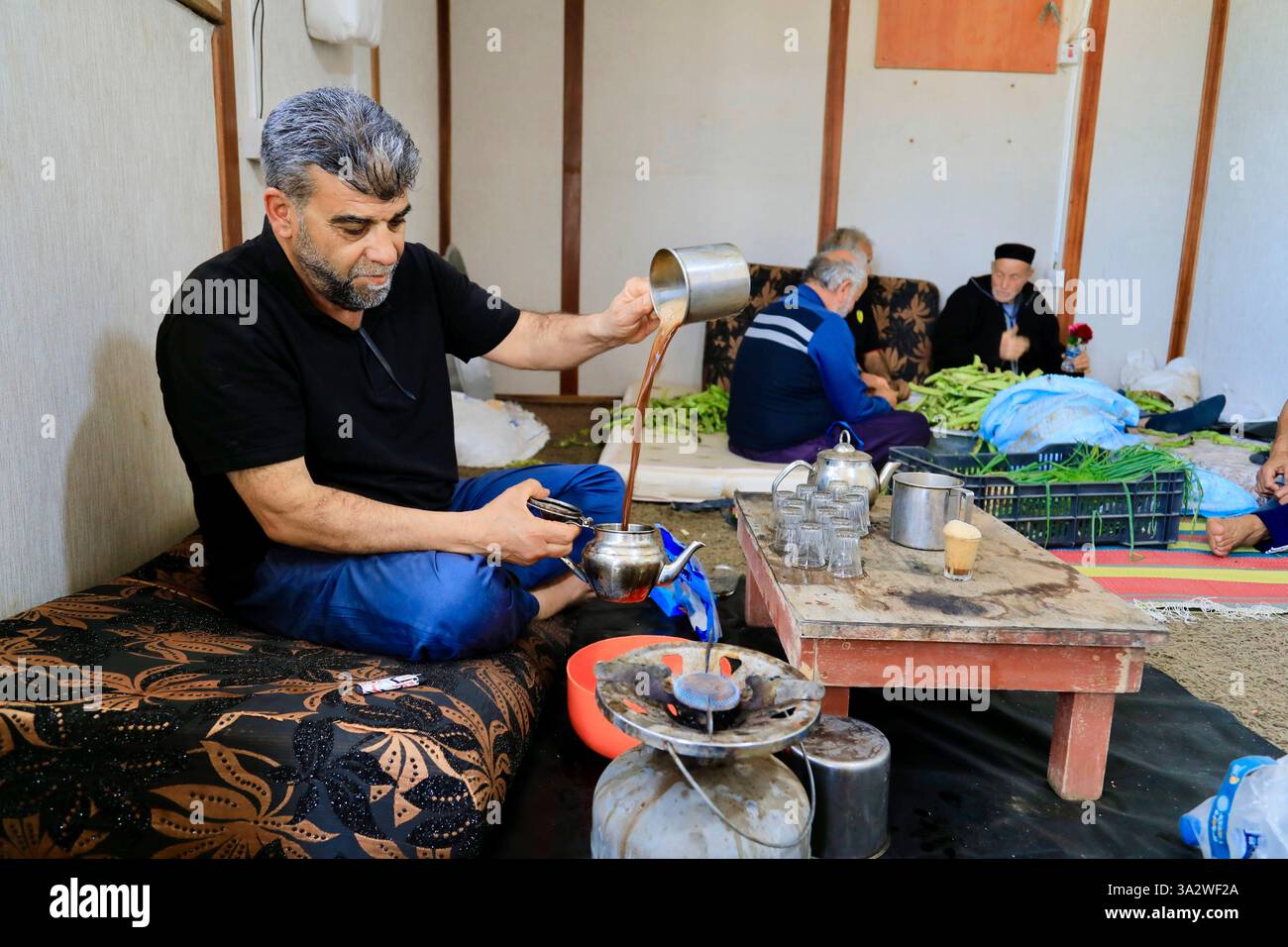 A man serves tea as volunteers prepare Bazin, a traditional Libyan ...