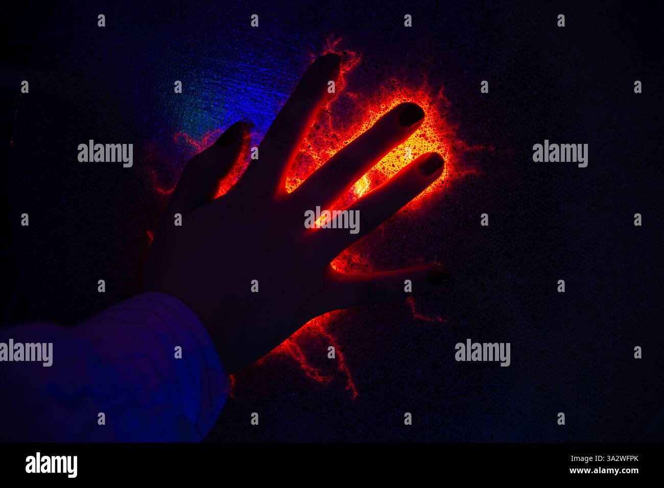 Orange plasma filaments reaching out to a child's hand interacting with ...