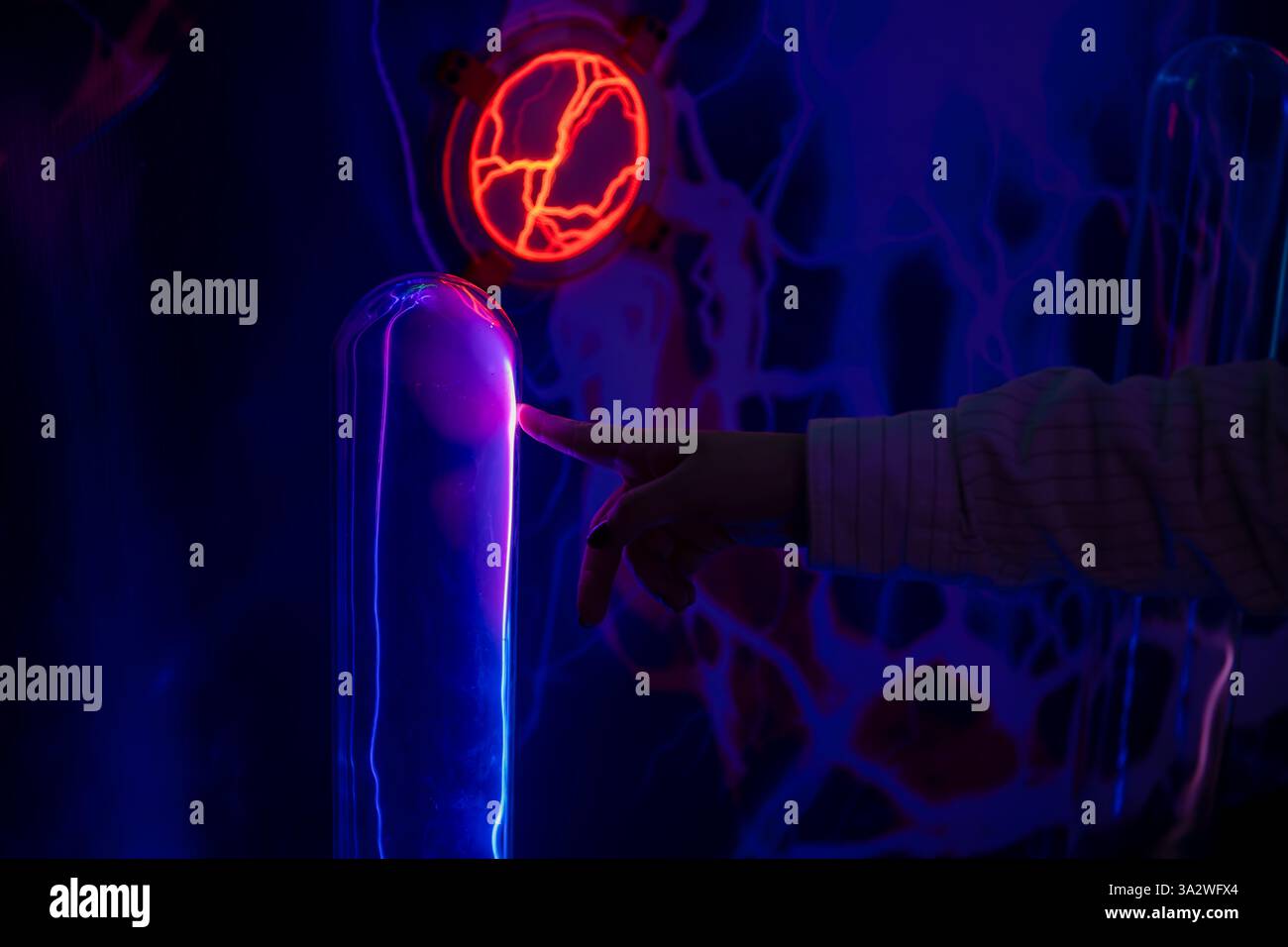 hand touches a glowing plasma ball in a dark laboratory, creating a ...