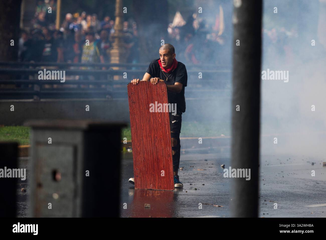 A young protester shields himself behind a piece of wood as the ...