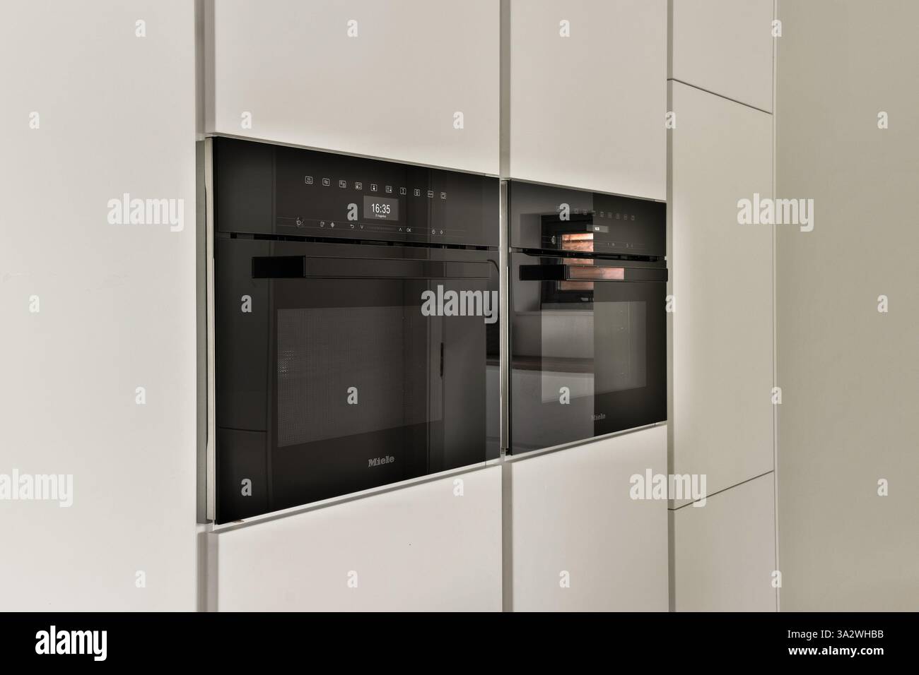 Sleek built-in kitchen ovens with black glass fronts and seamless ...