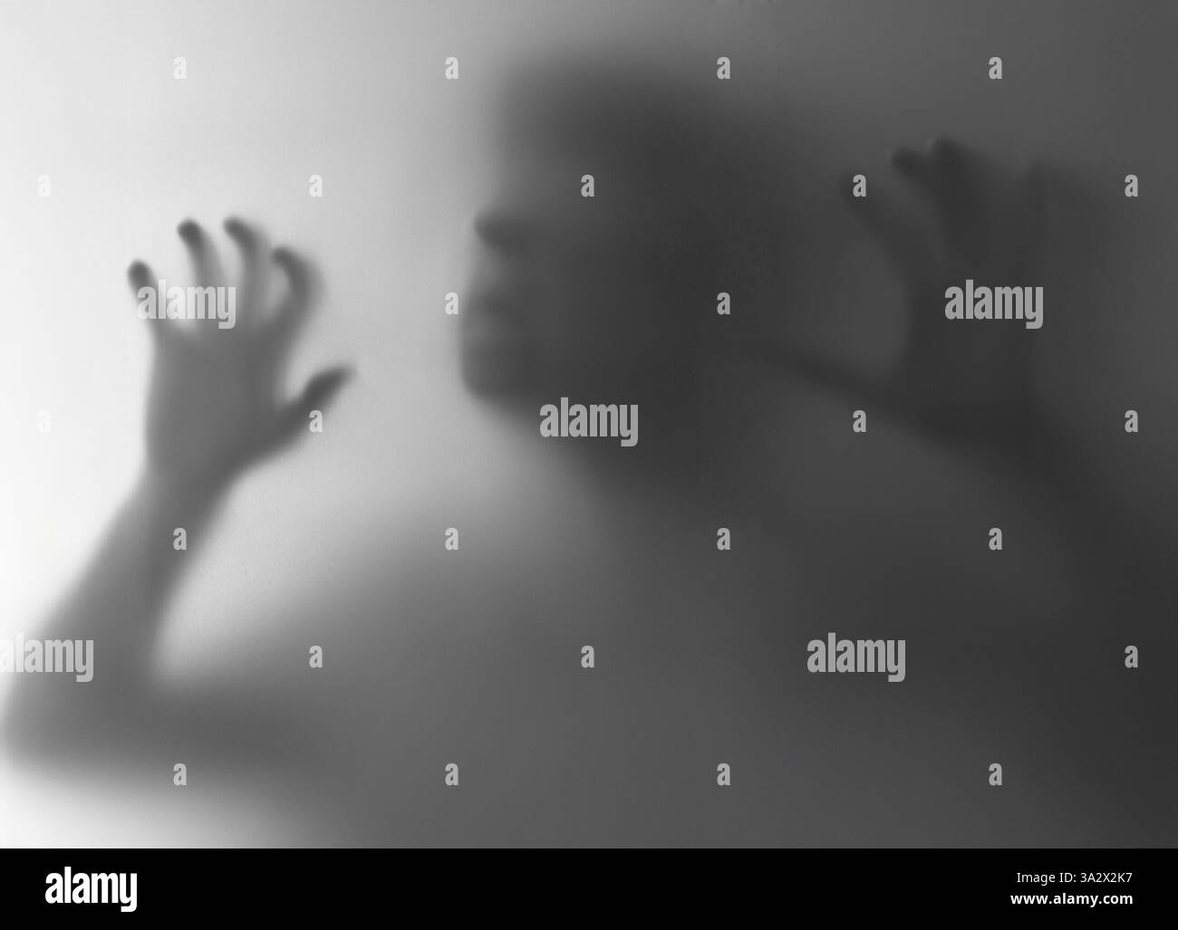 Eerie and enigmatic photograph of a person's silhouette pressed against a frosted glass surface ...