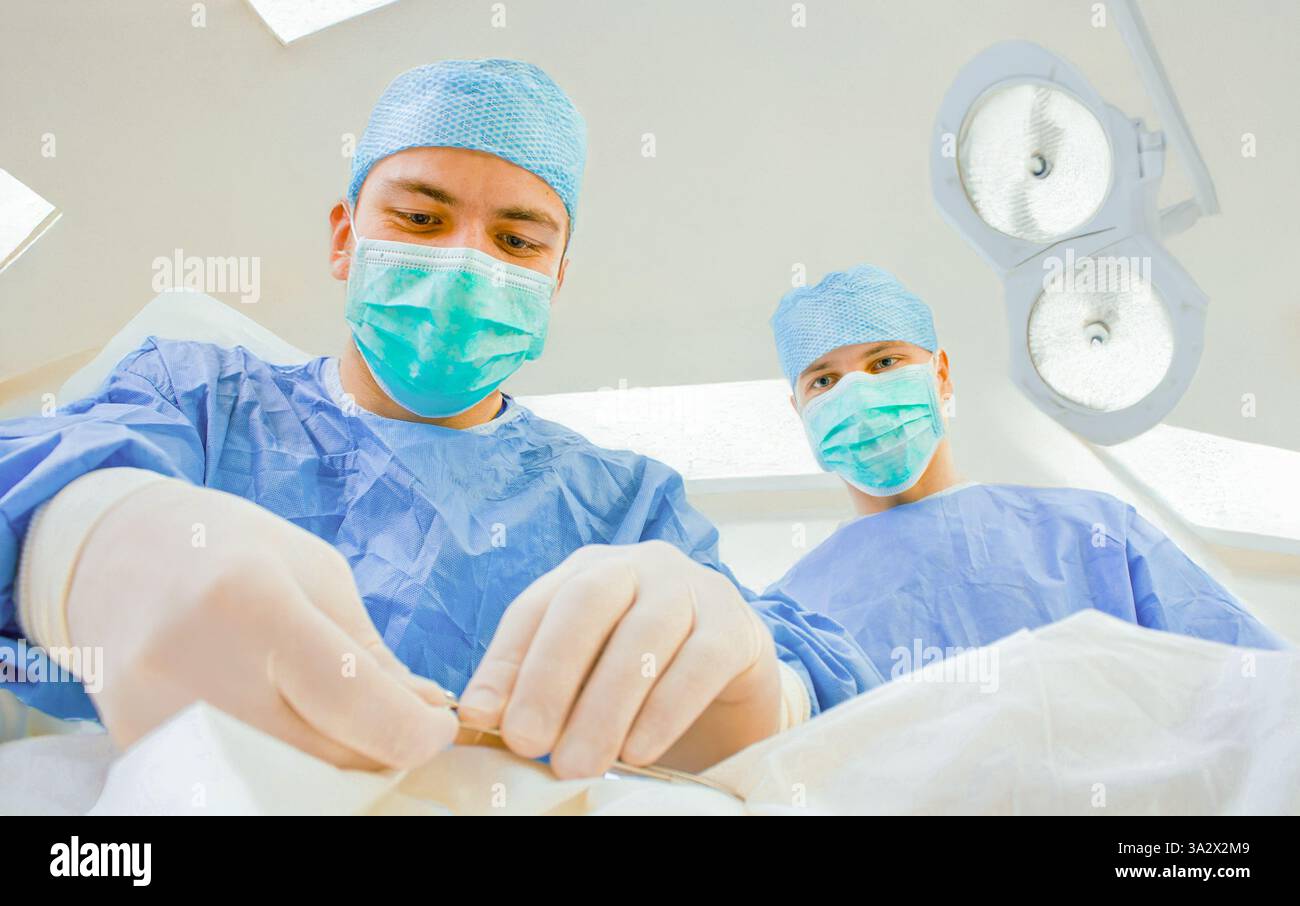 Medical surgeons wearing surgical attire and masks operate under ...