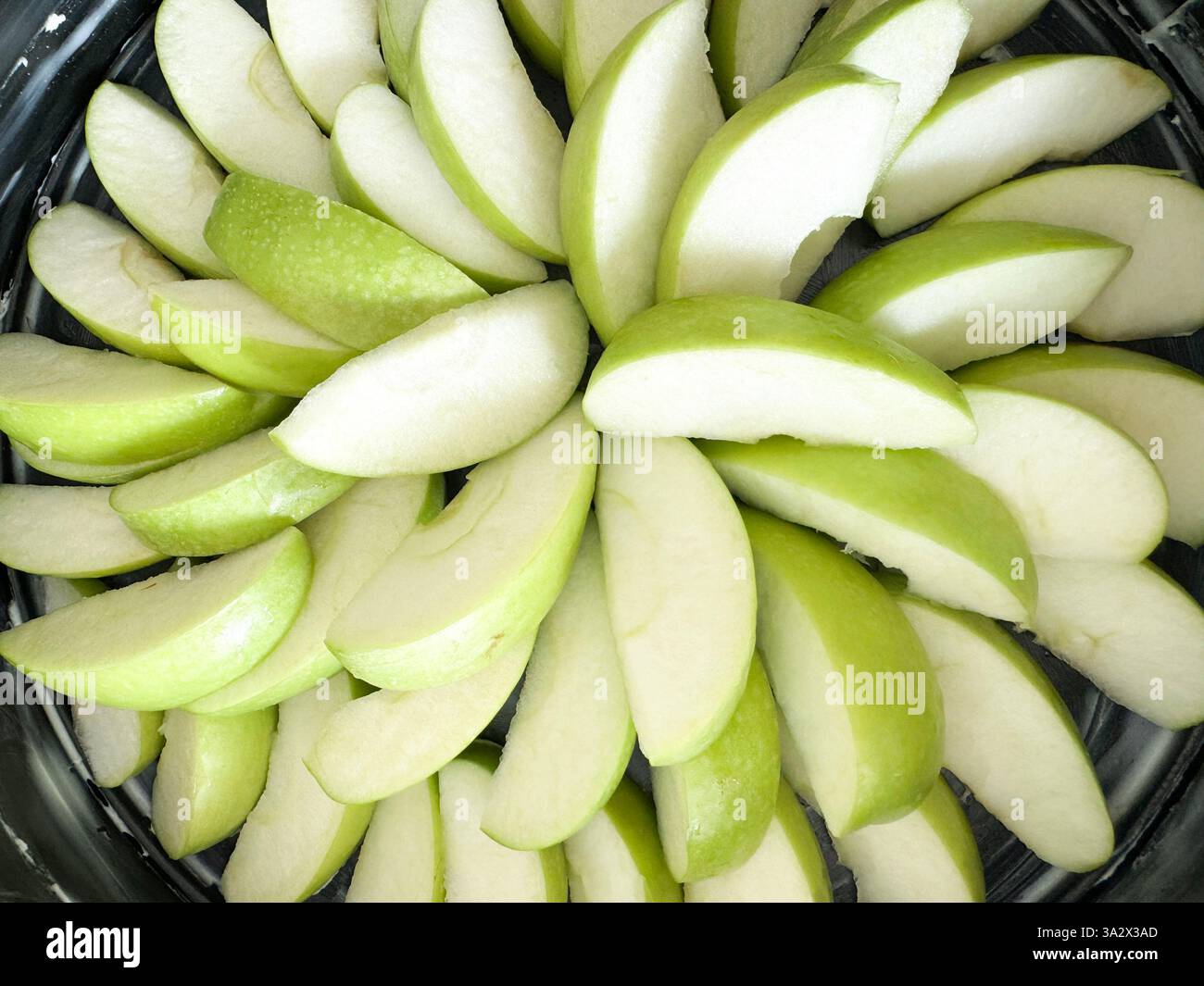 Fresh green apple slices are meticulously arranged in a circular ...