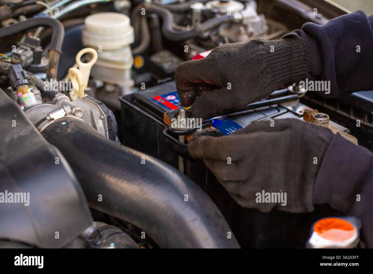 Replacing a car battery. The mechanic installs the battery, securing ...