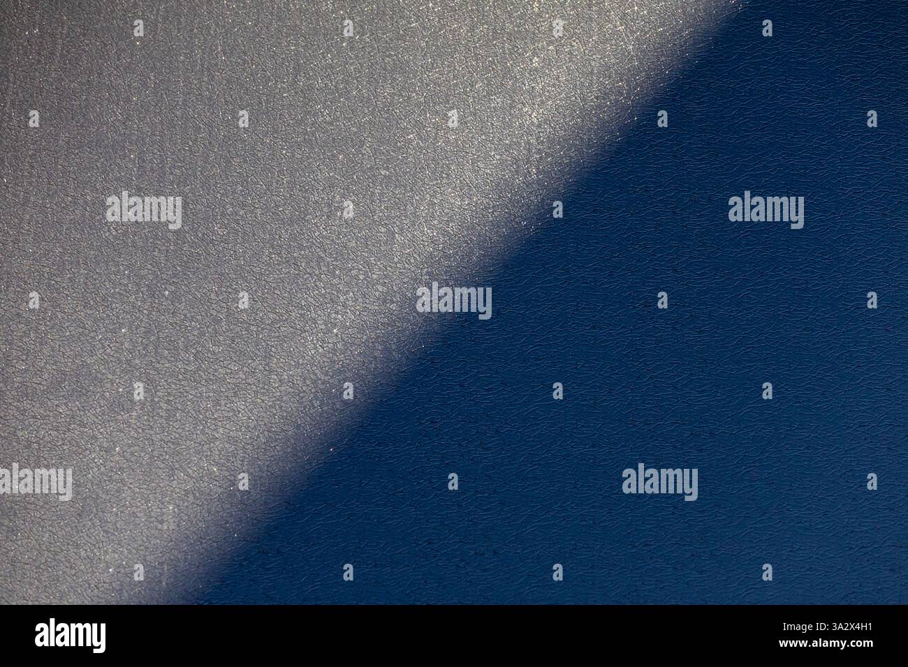 Intricate lines on a black plastic facade, with a diagonal shadow ...