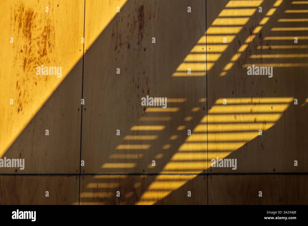 An intriguing shadow falls across a yellow wooden facade where worn ...