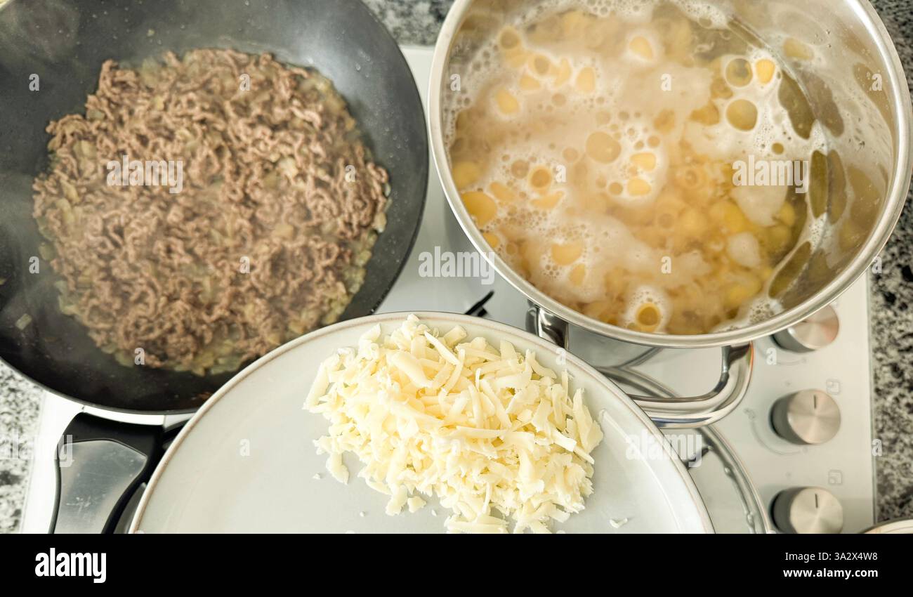 Cooking ground beef and boiling noodles in a modern kitchen setting ...
