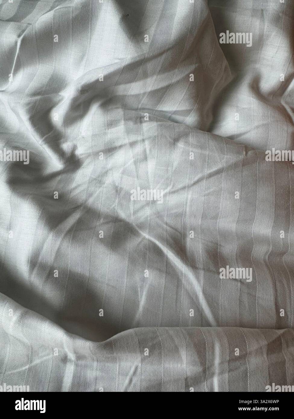 Soft white fabric draped elegantly on a surface creating gentle folds and shadows Stock Photo ...