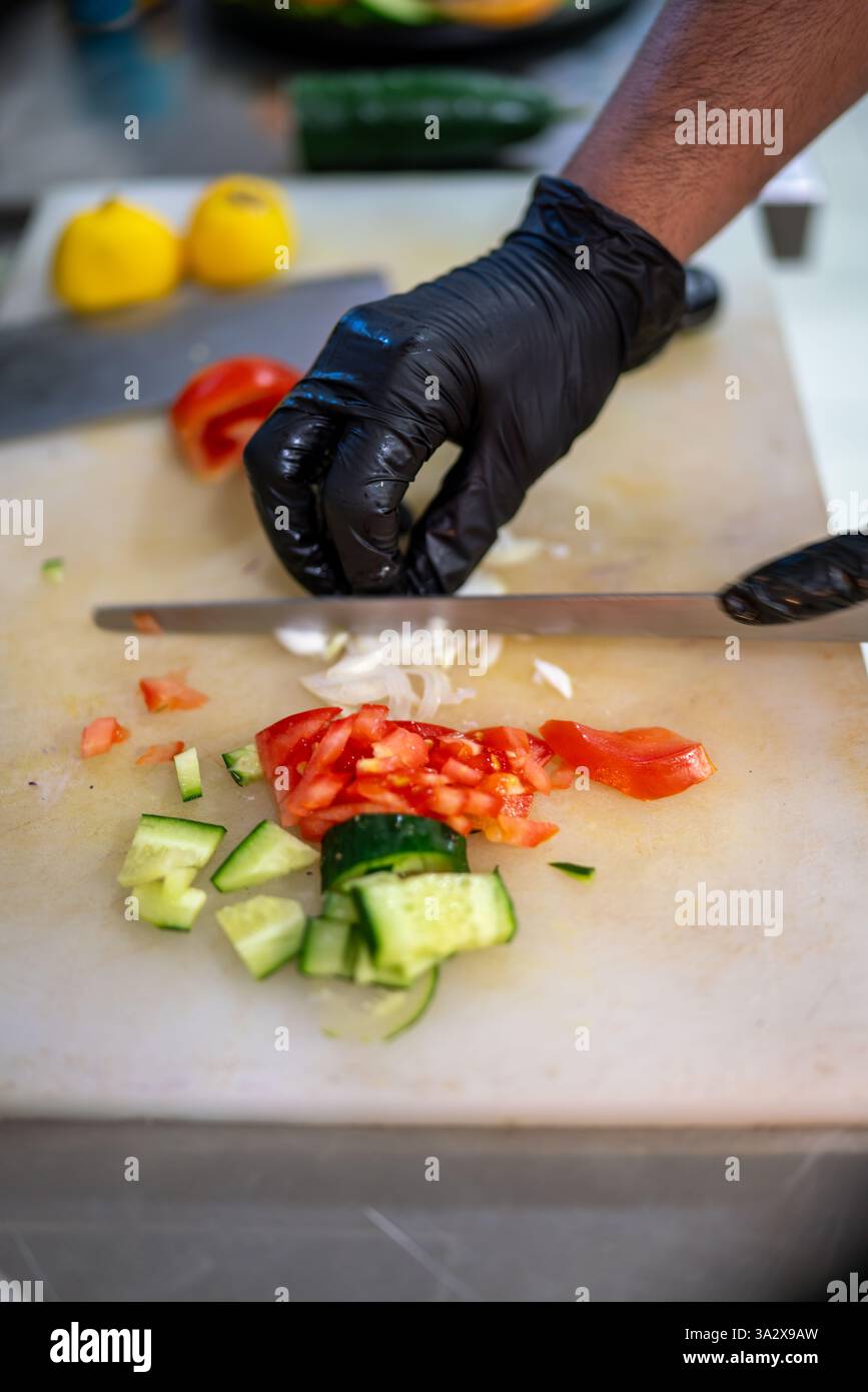 Gloved hand picking up chopped onions on a cutting board with other ...