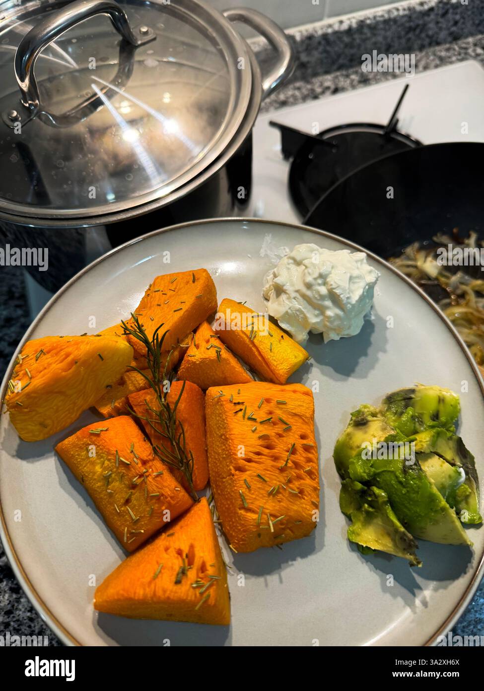 A plate displays colorful roasted pumpkin pieces, a dollop of cream ...