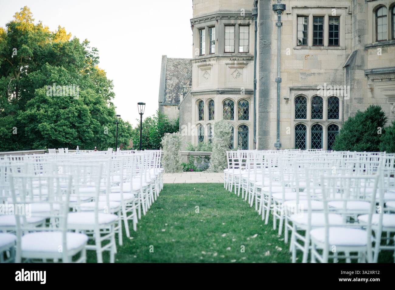 Outdoor wedding ceremony setup with white chairs and mansion venue ...