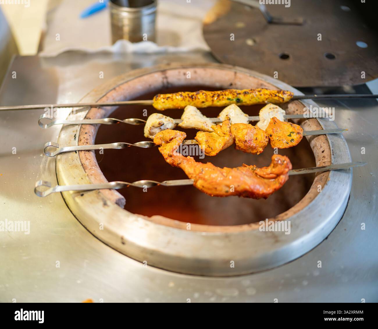 Chicken, fish, and paneer tikka are cooking in a traditional clay ...