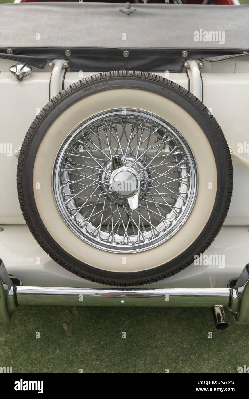 Close-up of a vintage spare wire-spoke wheel on a back of convertible ...