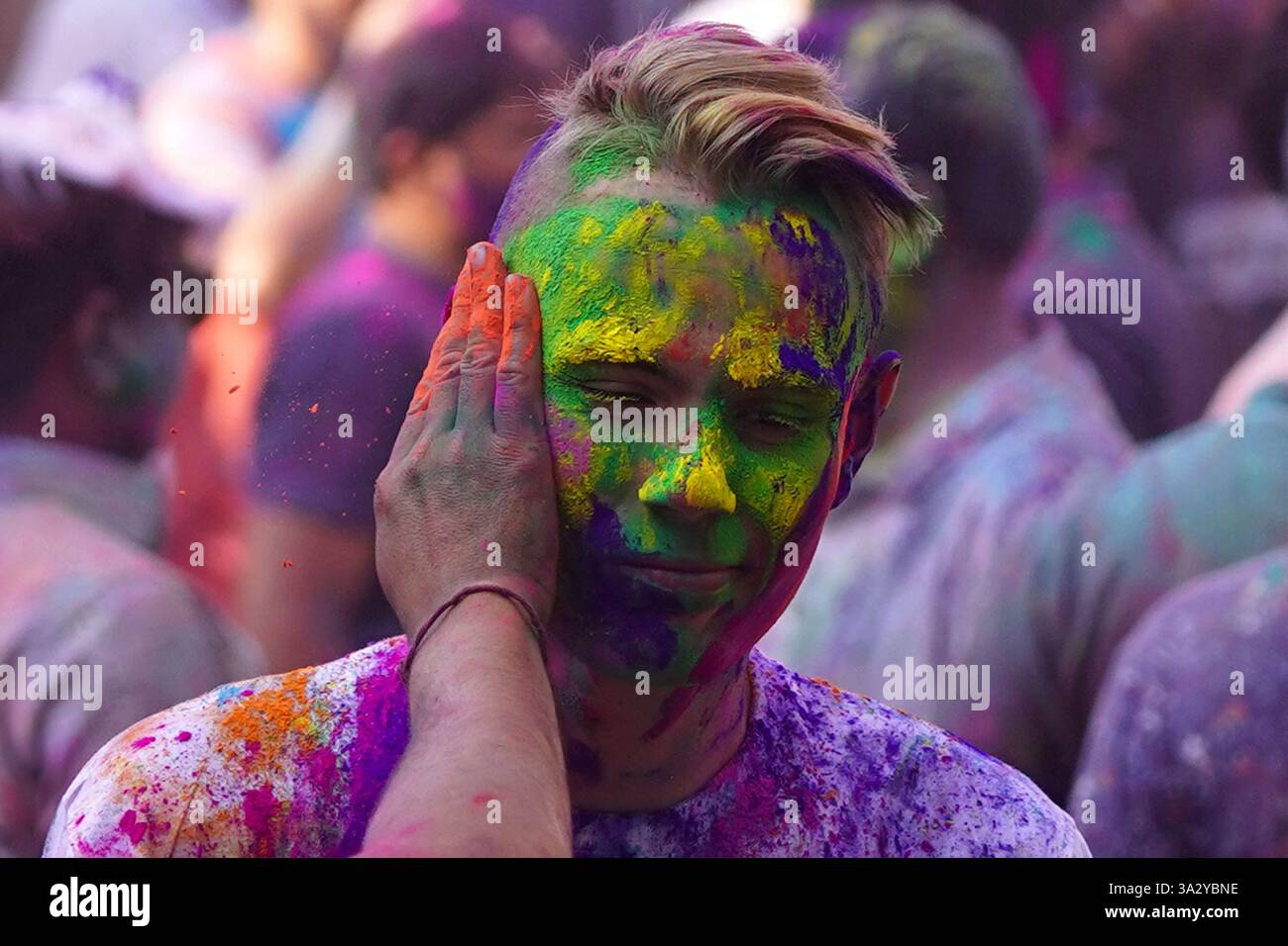 Pushkar, India. 14th Mar, 2025. Indian people dance as they throw colored powder and spray water ...