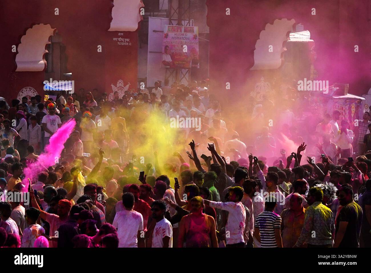 Pushkar, India. 14th Mar, 2025. Indian people dance as they throw colored powder and spray water ...