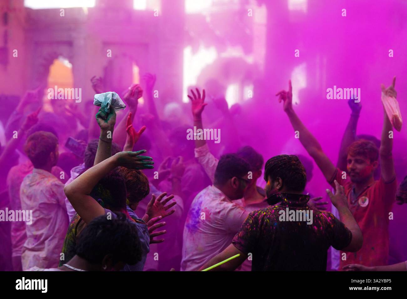 Pushkar, India. 14th Mar, 2025. Indian people dance as they throw colored powder and spray water ...