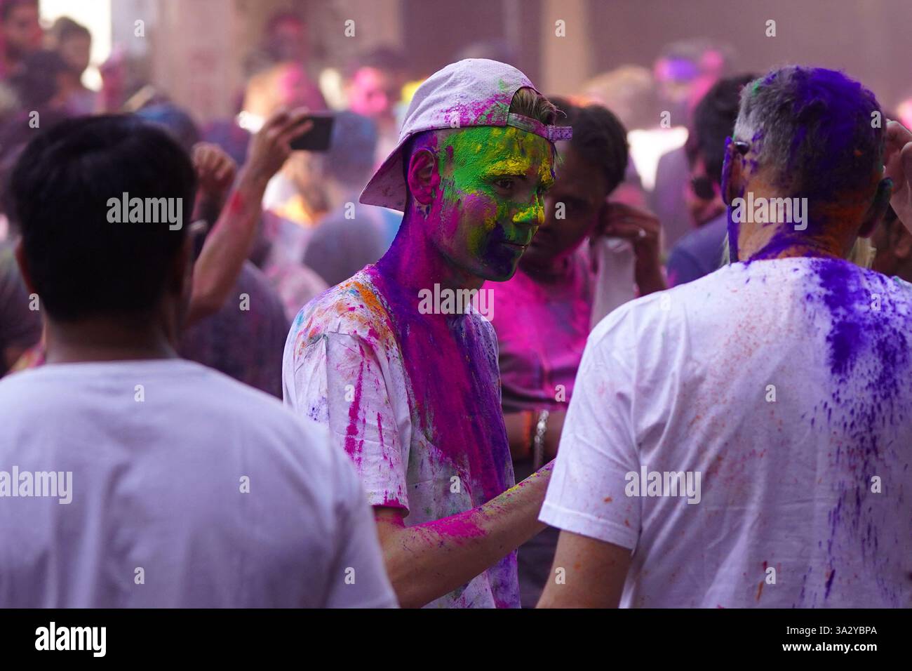 Pushkar, India. 14th Mar, 2025. Indian people dance as they throw colored powder and spray water ...