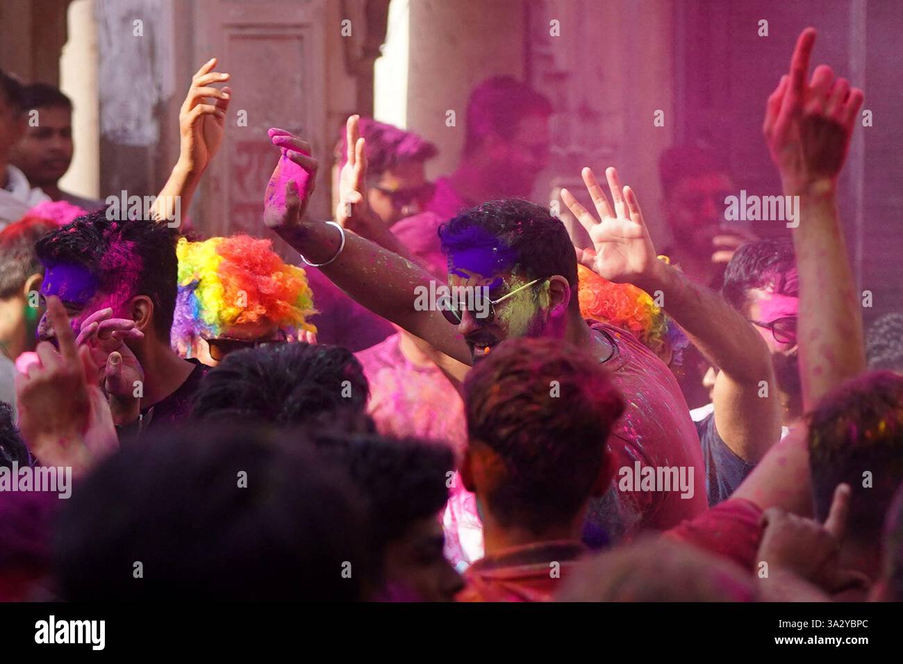 Pushkar, India. 14th Mar, 2025. Indian people dance as they throw colored powder and spray water ...