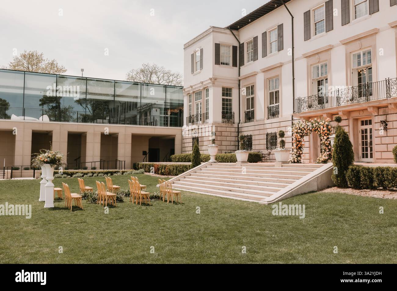 Elegant outdoor wedding setup with floral arch in front of a mansion ...