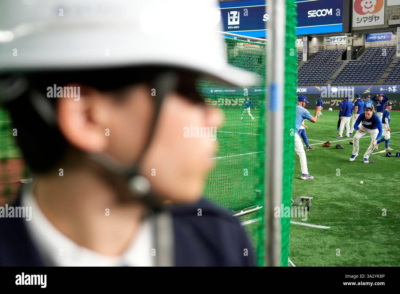 Los Angeles Dodgers players warm up as a security guard stands guard ...