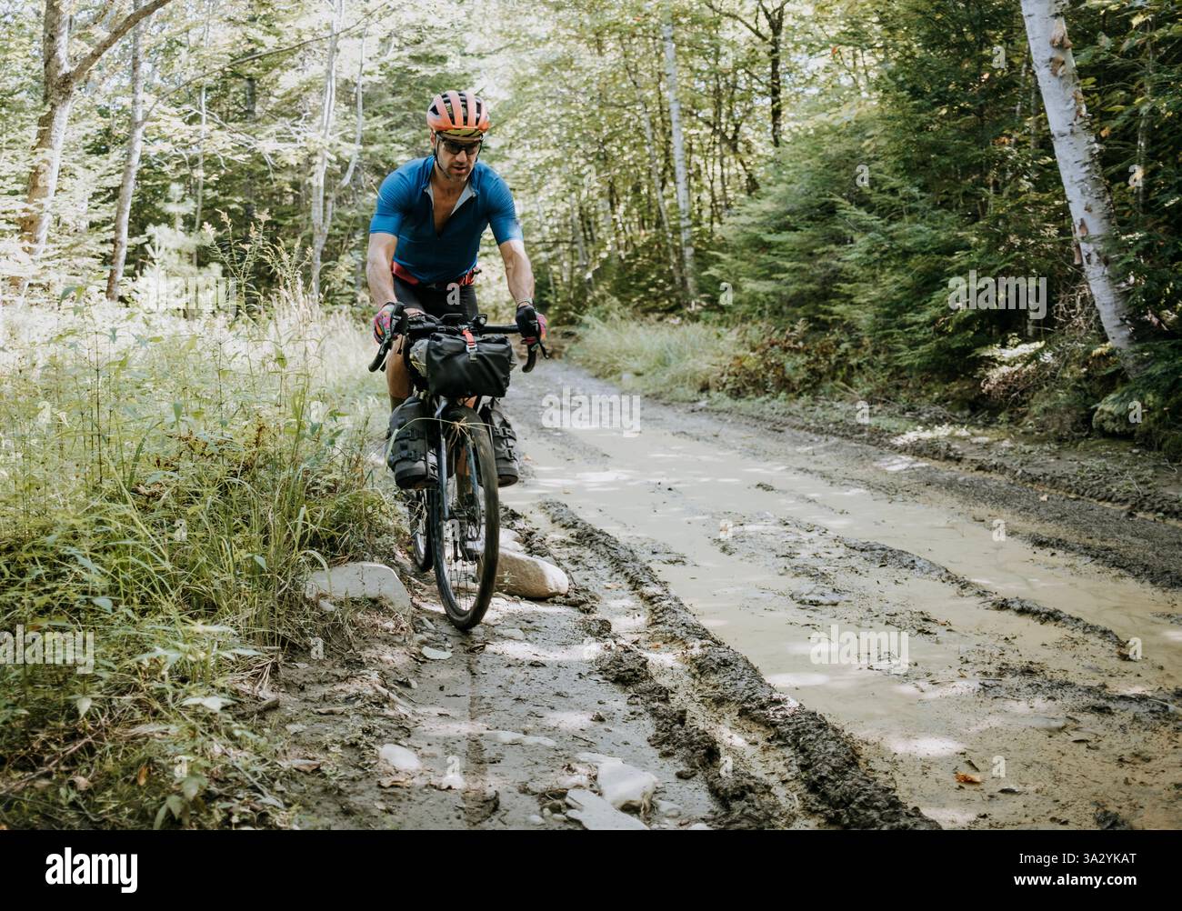 Male cyclist rides gravel bike along muddy dirt road in Maine Stock Photo - Alamy