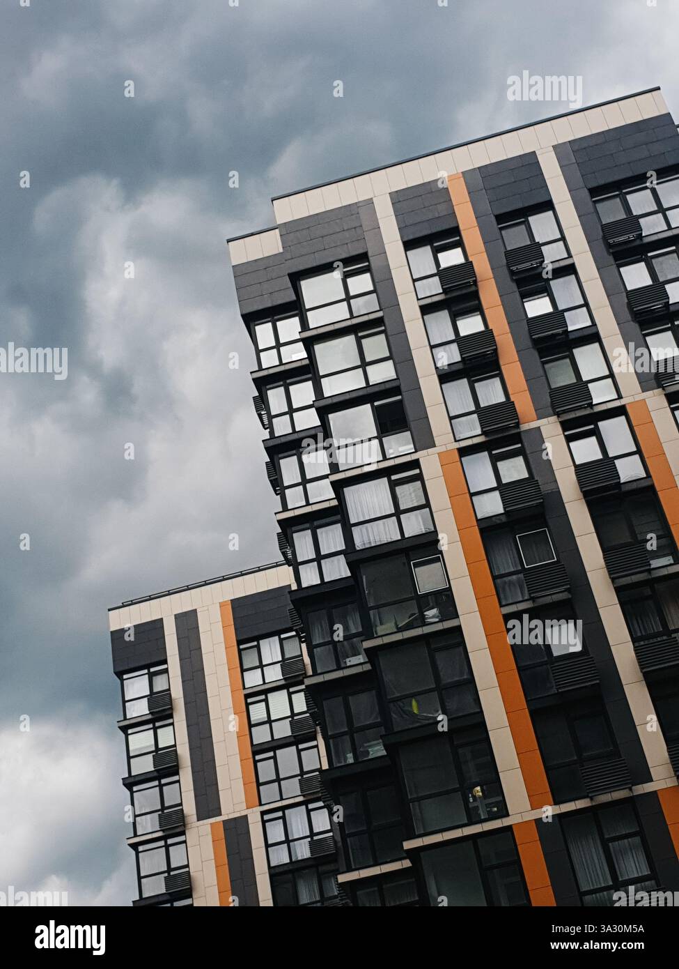 Modern residential building against cloudy sky. Dark grey apartment ...