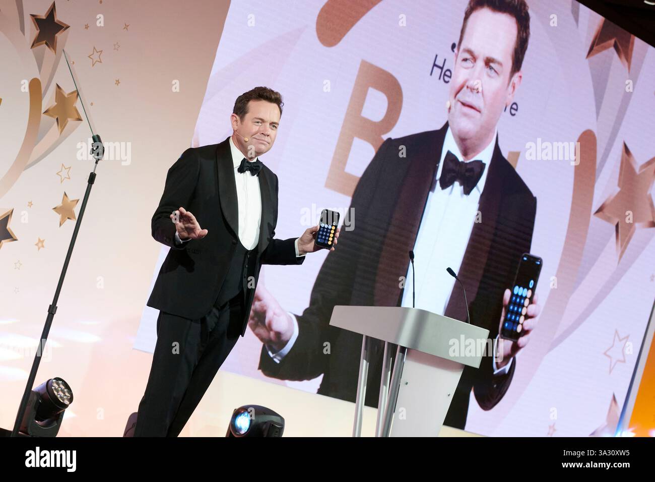 Stephen Mulhern in a tuxedo performing magic tricks on stage at a ...