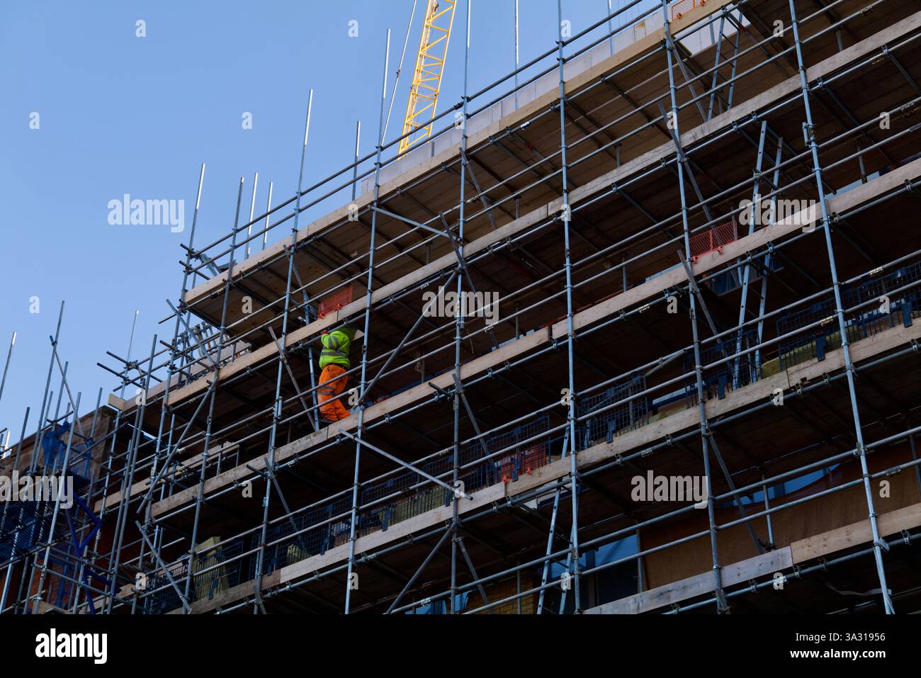 Scaffolding covers an old industrial building that's being converted ...