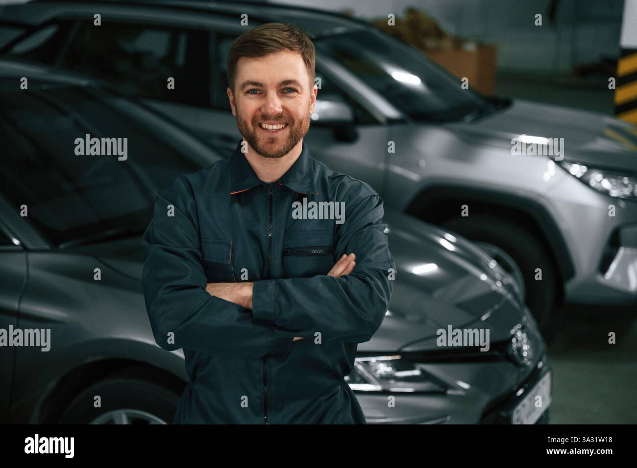 Repairman in uniform is standing in the garage with cars Stock Photo ...
