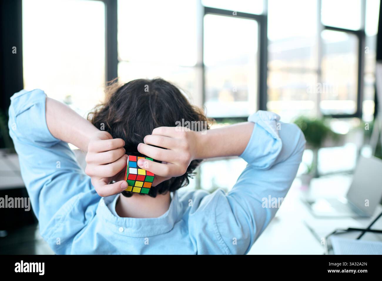 A young man with striking features takes a moment to unwind, solving a Rubiks cube at work Stock ...