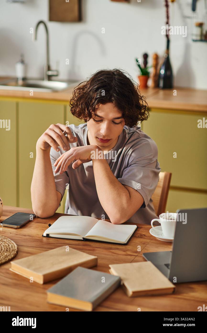 A good looking young man thoughtfully engages with his notepad while ...