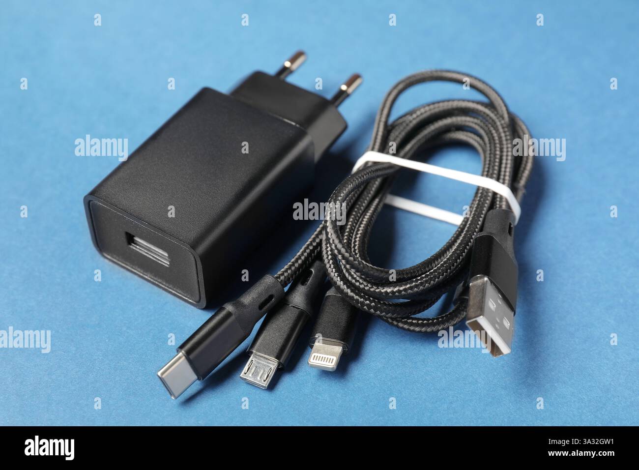USB power adapter and triple charge cable on light blue background ...
