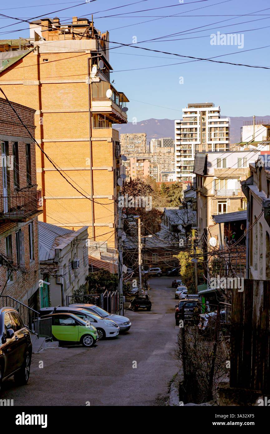 A quiet urban street with parked cars, warm sunlight on brick buildings ...