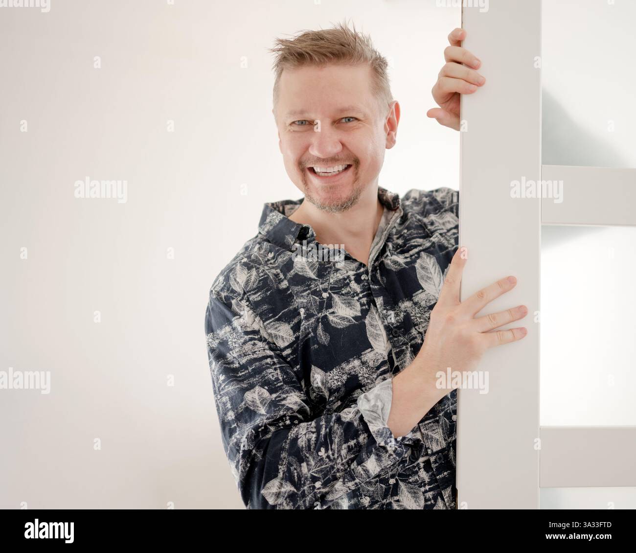 Happy Man Peeking Behind Door At Home Stock Photo - Alamy