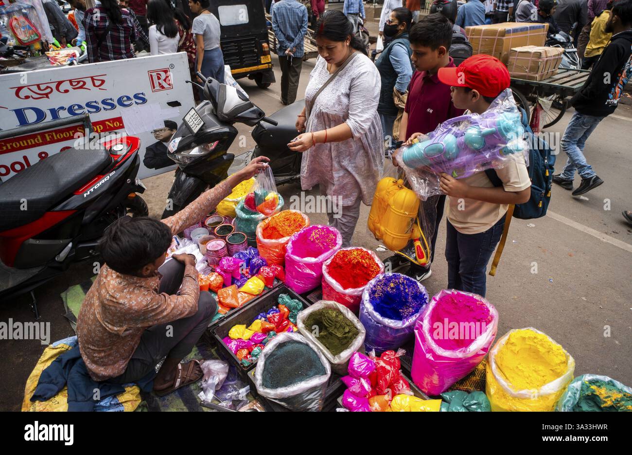 People buy coloured powder in a market on the eve of Holi Festival, on ...