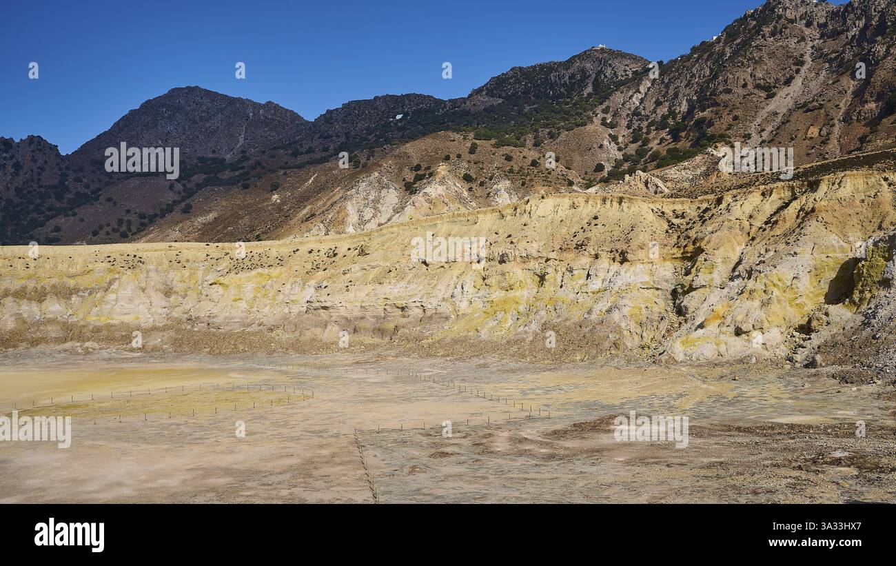 Barren volcanic crater landscape with mountains under a clear blue sky ...
