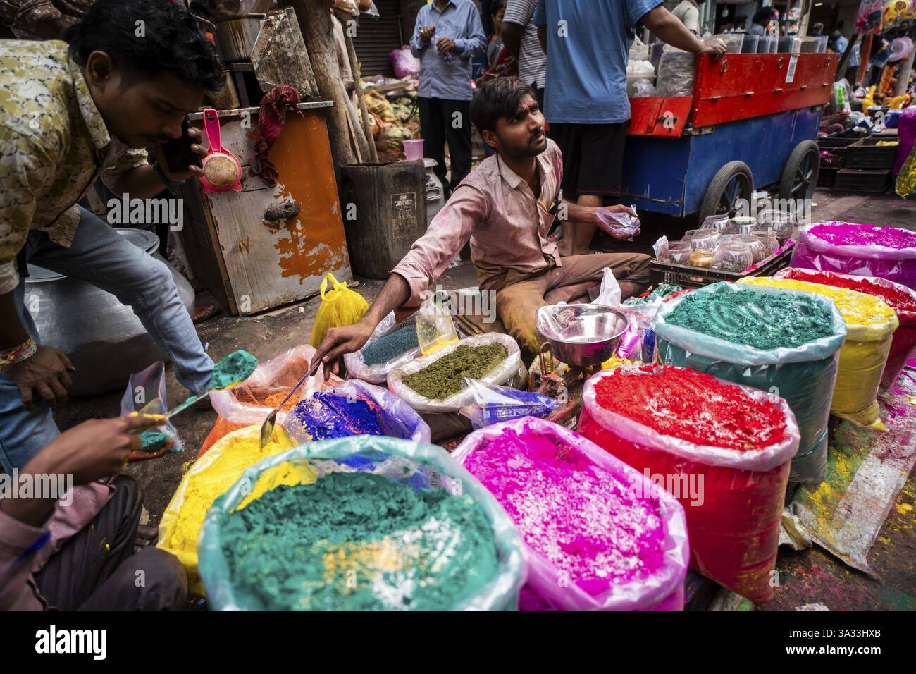 People buy coloured powder in a market on the eve of Holi Festival, on ...