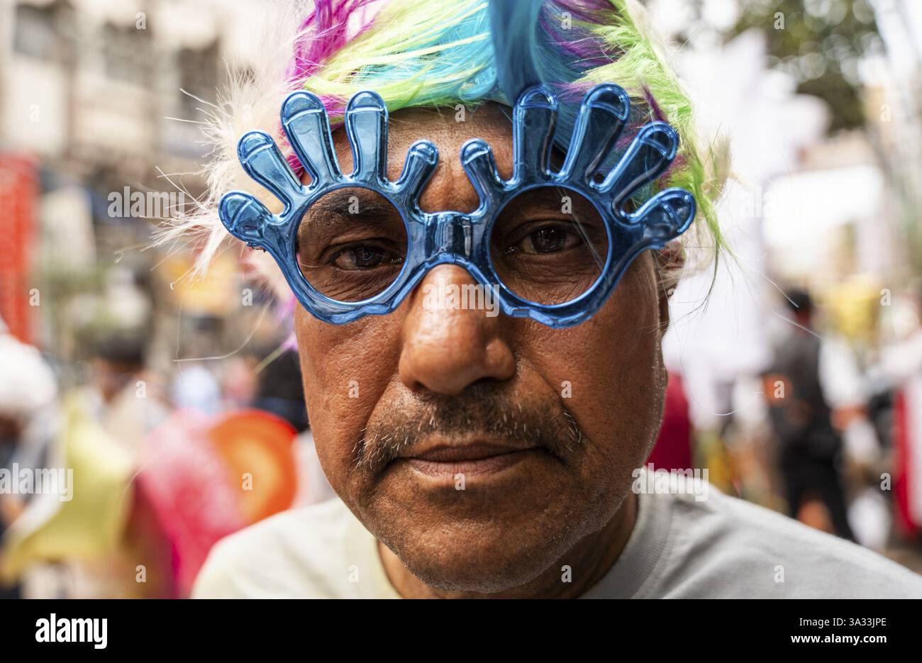 A person wears a holi sunglass in a market on the eve of Holi Festival ...
