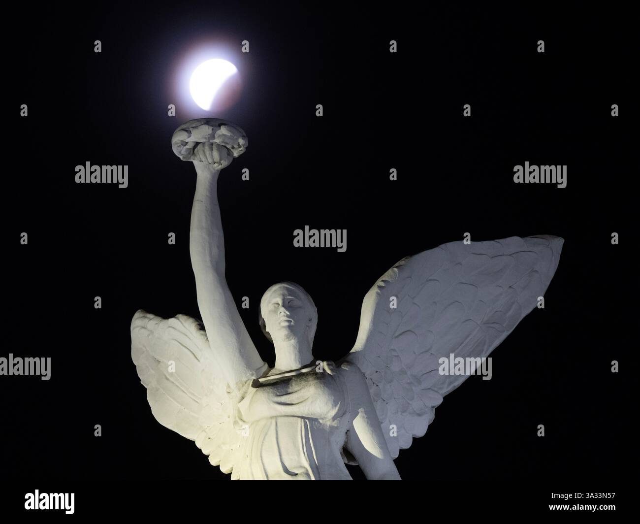 The blood moon lunar eclipse is seen behind a statue on the Princes ...