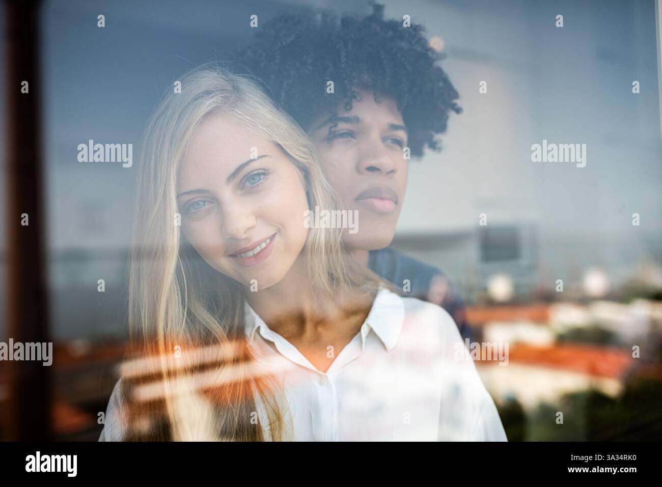 A reflective image of a diverse couple gazing through a window. Natural ...